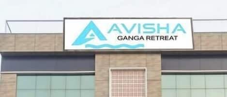 Um edifício com uma placa indicando 'AVISHA GANGA RETREAT' e uma grande janela vertical.