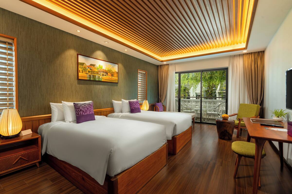 Quarto de hotel com duas camas, teto de madeira, um quadro na parede, janela com cortinas e uma varanda com vista.