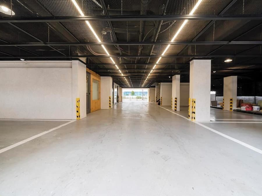 Um amplo espaço de estacionamento coberto, com piso de concreto e vigas de metal.