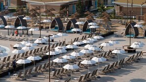 Resort com várias acomodações tipo bangalô, áreas de estar ao ar livre com guarda-sóis e vista para o oceano.