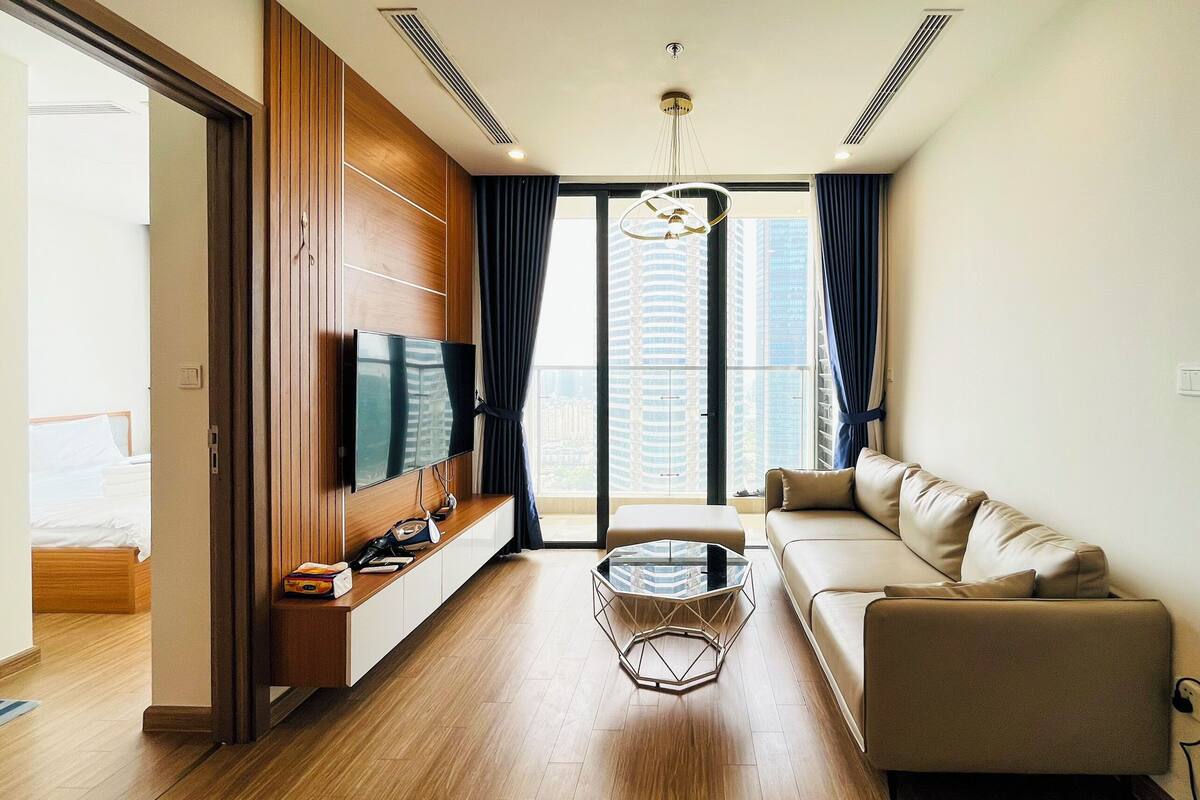 Uma sala de estar moderna com televisão de tela plana, painéis de madeira, um sofá e uma mesa de centro de vidro.