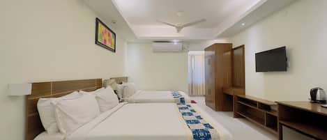 Quarto de hotel com duas camas, televisão, escrivaninha e guarda-roupa.