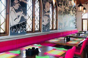 Um restaurante com um balcão comprido, jogos americanos coloridos e um mural na parede.
