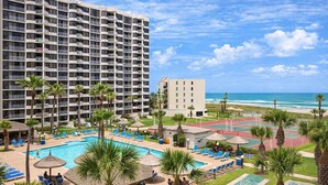 Um hotel com uma piscina grande, palmeiras e vista para o oceano.