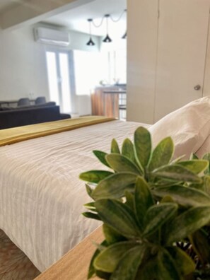 Quarto com cama, cabeceira de madeira e planta em vaso.