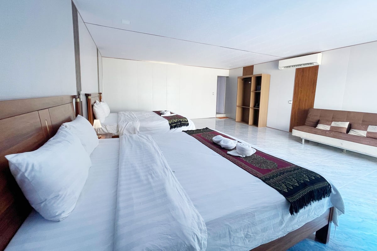 Quarto de hotel moderno com uma cama grande, um sofá e um guarda-roupa.