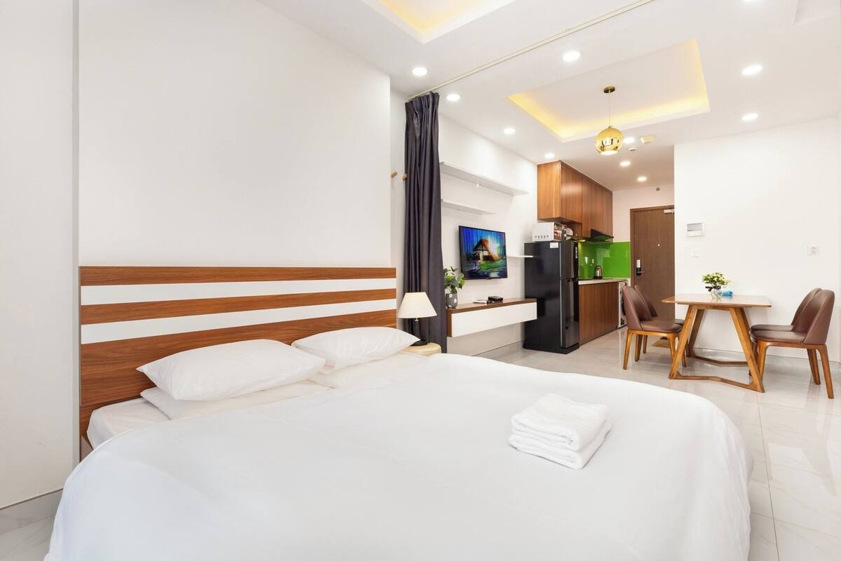 Quarto de hotel moderno com uma cama grande, uma kitchenette pequena e uma área de refeições.