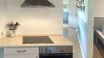 Uma cozinha moderna com exaustor de aço inoxidável, forno embutido e bancada de granito.