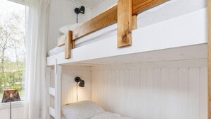 Uma cama de beliche com cabeceira de madeira, uma luminária de cabeceira e uma janela com cortinas.