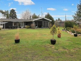 Imóvel residencial com varanda coberta, gramado e plantas em vasos.