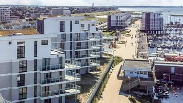 Uma área residencial moderna com edifícios altos, uma marina com barcos e vista clara para o mar.