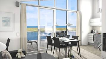 Quarto de hotel moderno com uma grande porta de correr de vidro que dá para uma varanda com vista para o mar.
