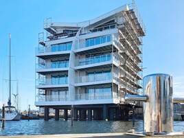 Um edifício de vários andares com design arquitetônico moderno, situado sobre a água.
