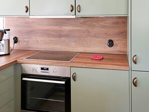 Cozinha equipada com forno embutido, micro-ondas e bancada de madeira.