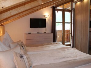 Quarto com cama, cômoda, televisão e janela com vista para o exterior.
