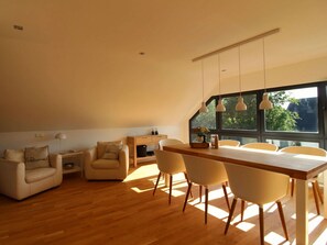 Loft moderno com área de jantar, sofá e escrivaninha.
