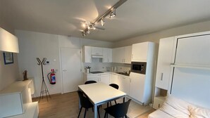 Uma cozinha compacta com armários brancos, micro-ondas e mesa de jantar com cadeiras.