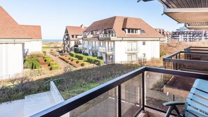 Edifício residencial com varanda com vista para um jardim ajardinado e outras casas.