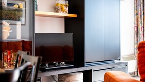 Uma sala de estar moderna com uma TV de tela plana, uma mesa de centro e uma estante.