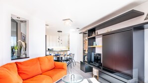 Uma sala de estar moderna com um sofá laranja vibrante, uma mesa de centro de vidro e um módulo de entretenimento preto.