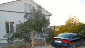 Uma casa com um carro estacionado em frente, uma árvore e vista para a paisagem.