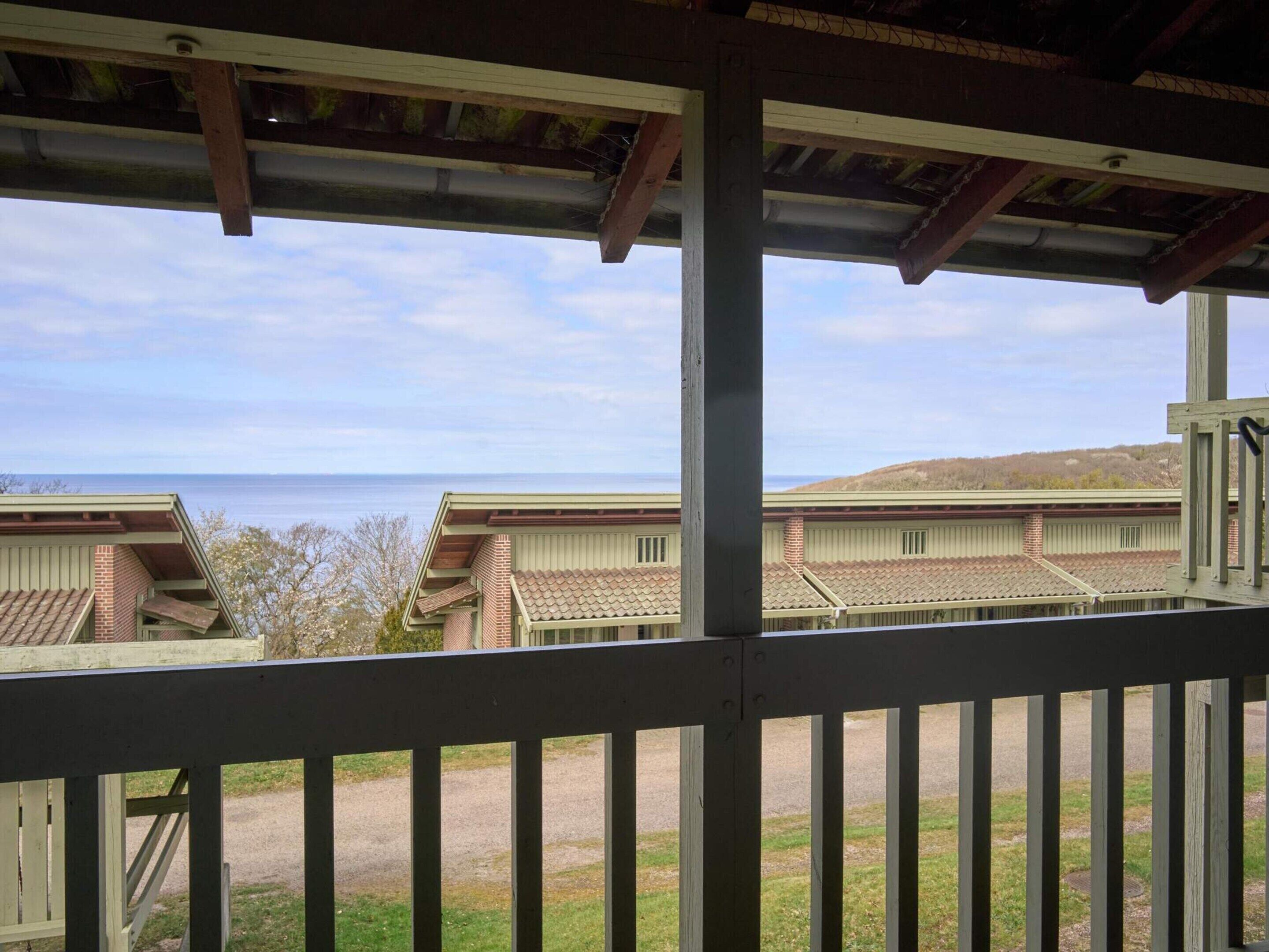Vista de uma varanda coberta com vista para uma praia e vários edifícios ao fundo.