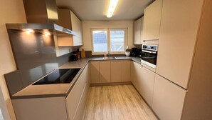 Cozinha compacta com fogão embutido, forno e janela que proporciona iluminação natural.