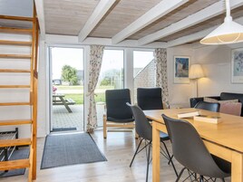 Quarto com mesa de madeira, cadeiras pretas, um banco de madeira, sofá e uma escada.