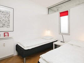 Quarto pequeno e limpo com uma cama, uma escrivaninha e um radiador.