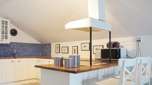 Uma cozinha moderna com armários brancos, bancada de madeira e uma cadeira branca.
