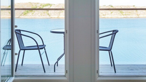 Varanda com duas cadeiras e uma mesa, com vista para um corpo de água.