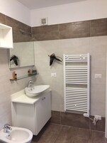 Casa de banho com lavatório, espelho, porta-toalhas e radiador branco.