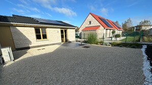 Um edifício com entrada por um caminho de cascalho e painéis solares no telhado.