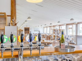 Uma área de bar com várias torneiras de cerveja, uma garrafa de vinho e copos no balcão.