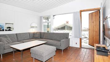 Uma sala de estar moderna com um sofá seccional cinza, uma mesinha e um aparador de madeira.
