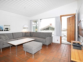 Uma sala de estar moderna com um sofá seccional cinza, uma mesinha e um aparador de madeira.