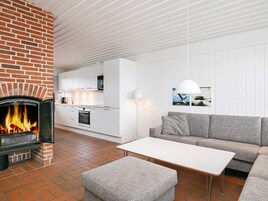 Uma sala de estar moderna com lareira, armários brancos, um sofá cinza e uma mesa de centro branca.