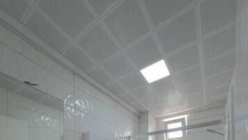 Casa de banho moderna com cabine de chuveiro em vidro, acessórios brancos e rolo de papel higiénico à vista.