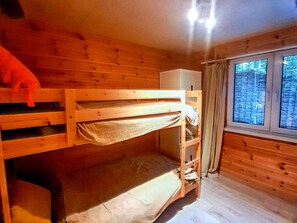 Quarto com beliche, janela e cortinas.