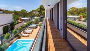 Varanda moderna com piscina, espreguiçadeiras e vista do bairro ao redor.