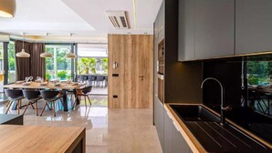 Uma cozinha moderna com uma pia preta, armários de madeira e uma área de refeições com mesa e cadeiras.
