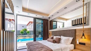 Quarto moderno com uma cama grande, um banco embutido, uma luminária no teto e vista para uma piscina.