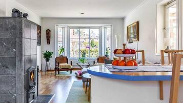 Uma sala de estar moderna com lareira, um espaço de jantar com uma seleção de frutas e grandes janelas com vista para o exterior.