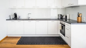 Uma cozinha moderna com armários brancos, bancada preta e tapete preto.