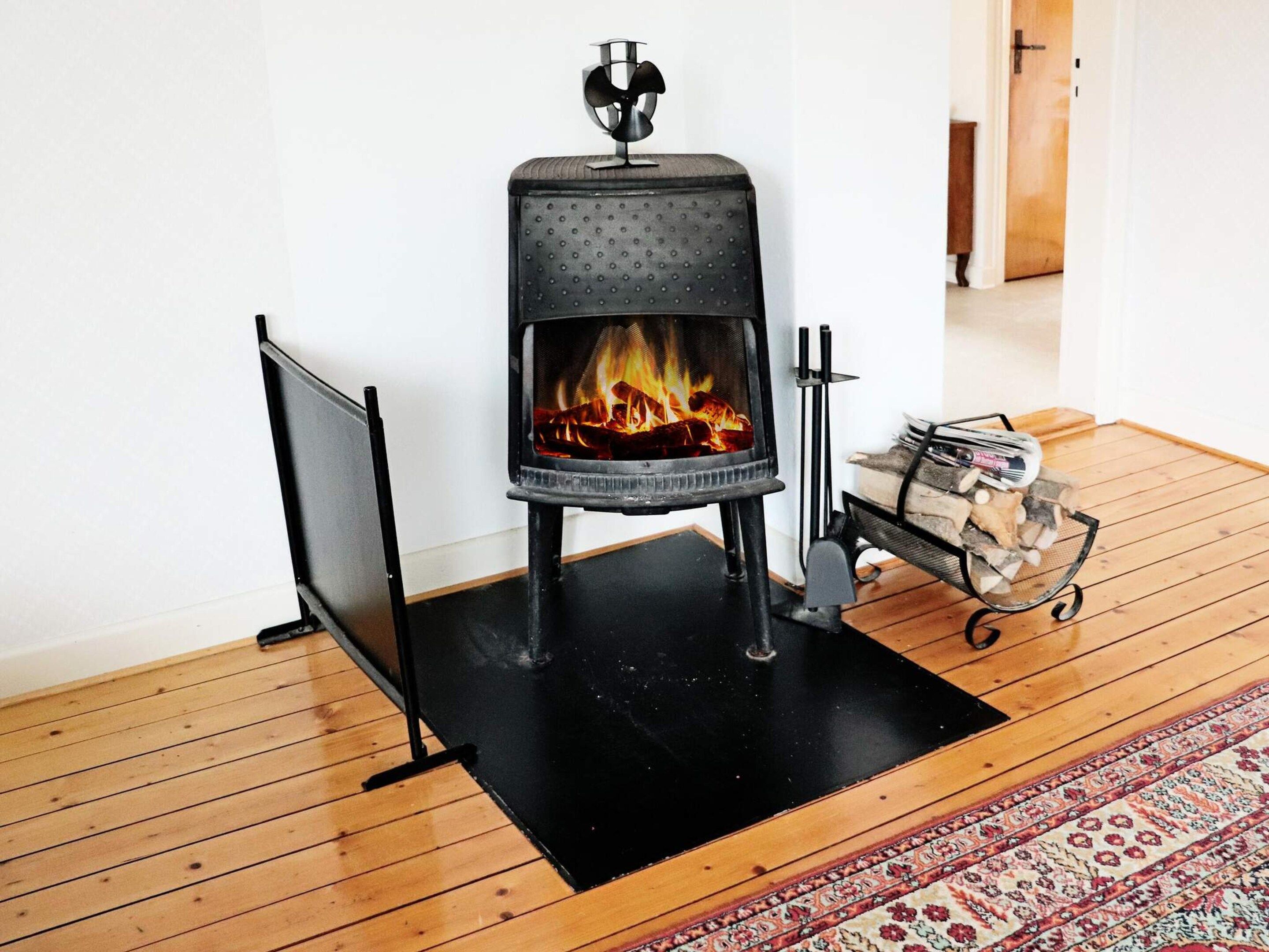 Lareira a lenha com fogo, um suporte de metal e uma pilha de lenha.
