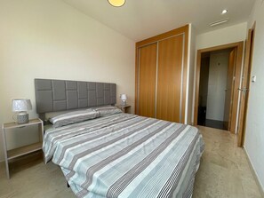 Quarto com cama, mesas de cabeceira, guarda-roupa e uma porta.