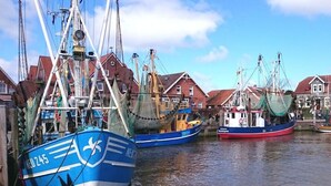 Um porto com vários barcos de pesca atracados, rodeado por edifícios com telhados vermelhos.