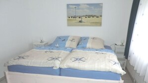Quarto com uma cama, duas mesas de cabeceira, um criado-mudo e um quadro na parede.