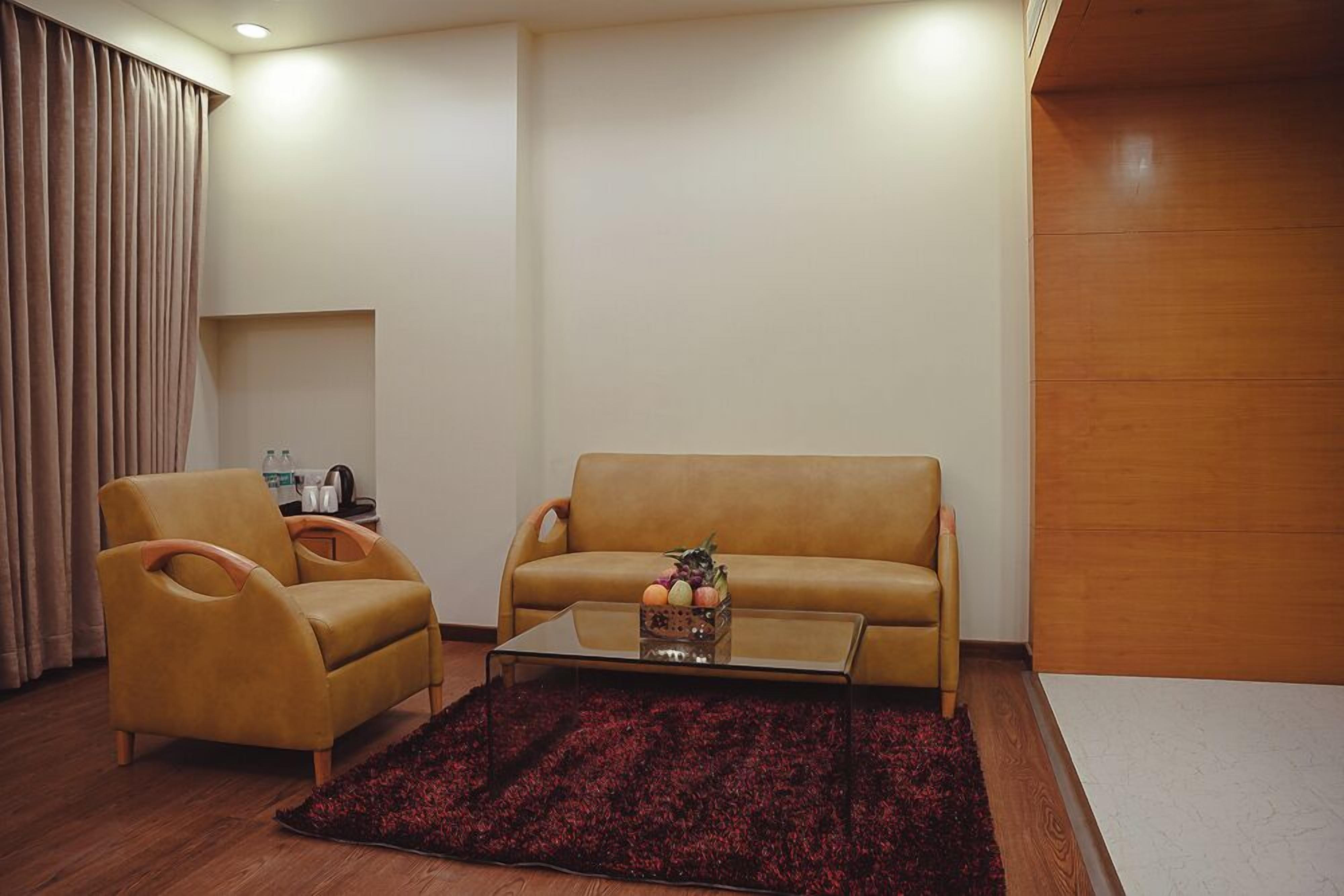 Sala de estar com sofá, poltrona e mesa de centro com frutas.