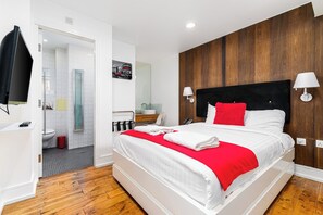Quarto moderno com uma cama grande, parede de painel de madeira, roupa de cama branca e um cobertor vermelho.